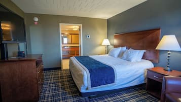 Quarto de hotel com cama, escrivaninha, cômoda, abajur e banheiro visível por uma porta aberta.