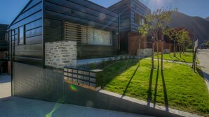 Uma casa moderna com telhado inclinado, janelas amplas e alicerce de pedra.