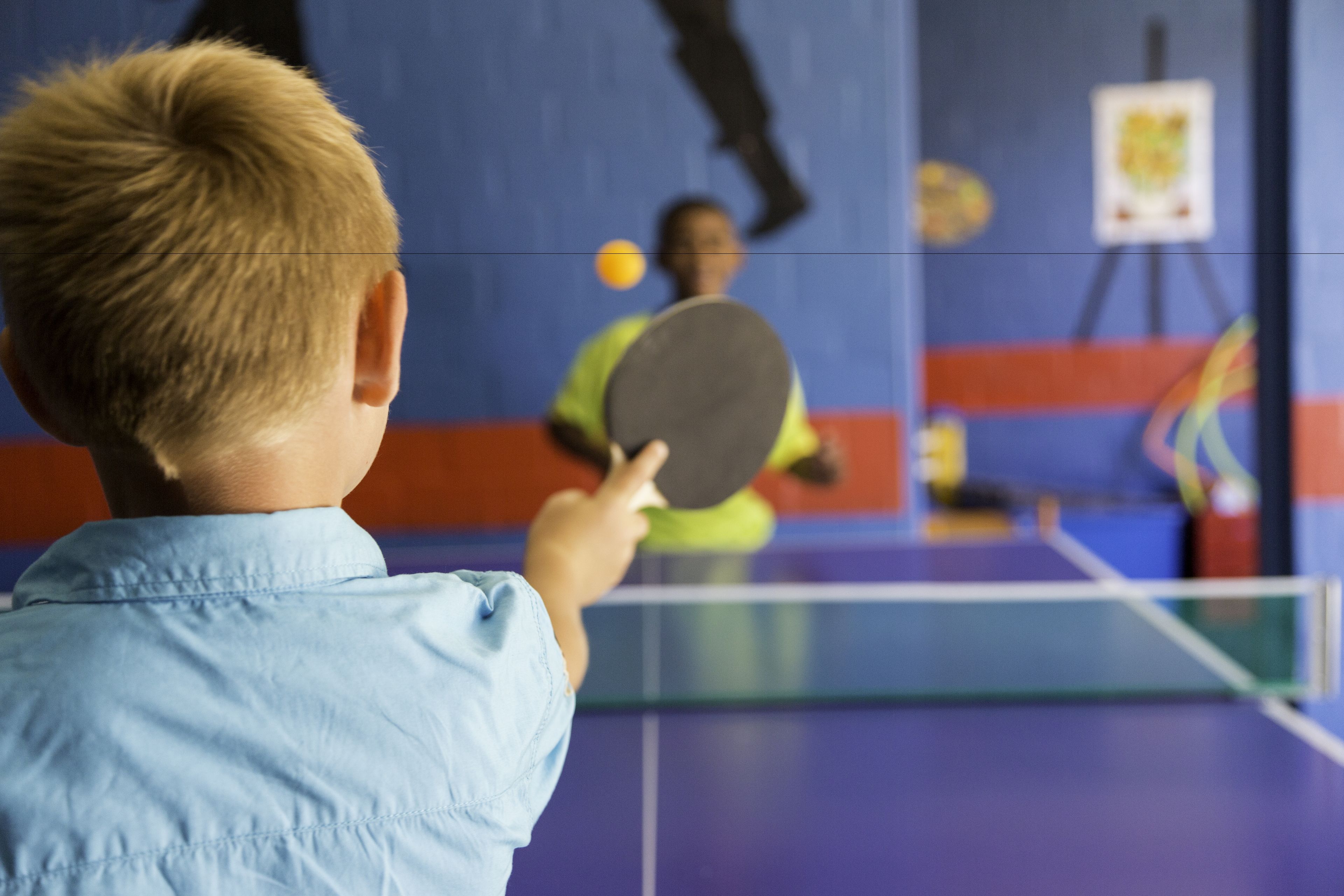 Criança jogando tênis de mesa.