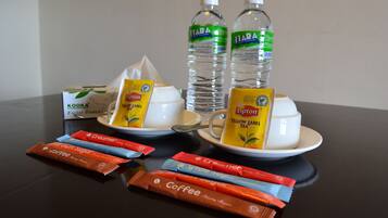 Uma mesa com duas chávenas de chá, duas garrafas de água e vários pacotes de café e leite.