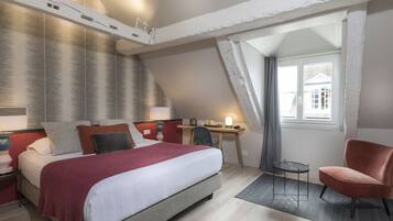 Um quarto com cama, mesas de cabeceira, escrivaninha, cadeira e janela com cortinas.