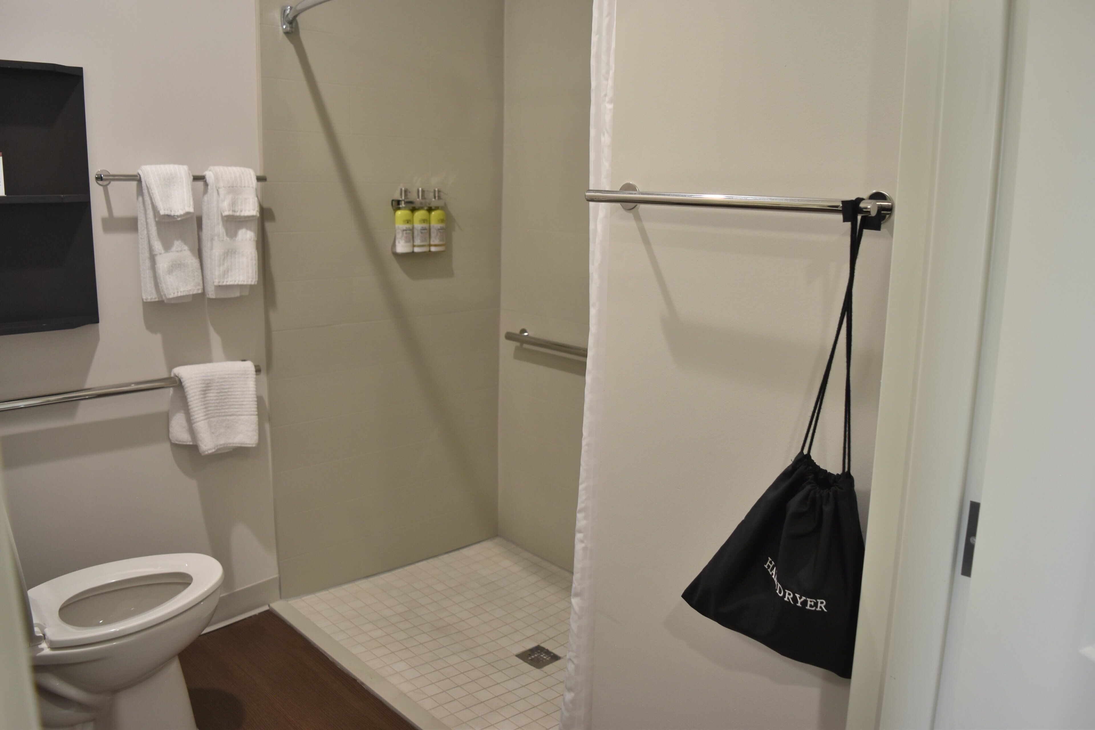 Uma casa de banho com sanita, cabine de duche e toalheiros com várias toalhas.