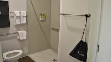 Uma casa de banho com sanita, cabine de duche e toalheiros com várias toalhas.