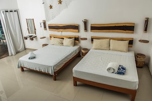 Quarto de hotel com duas camas, cabeceiras de madeira e uma decoração com estrela pendurada.