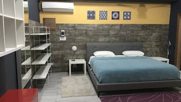 Quarto com cama, mesa de cabeceira, ar-condicionado fixado na parede e estante.