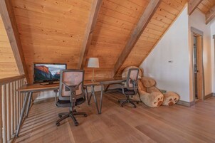 Teto de madeira com uma televisão sobre uma mesa, duas cadeiras de escritório e um ursinho de pelúcia.
