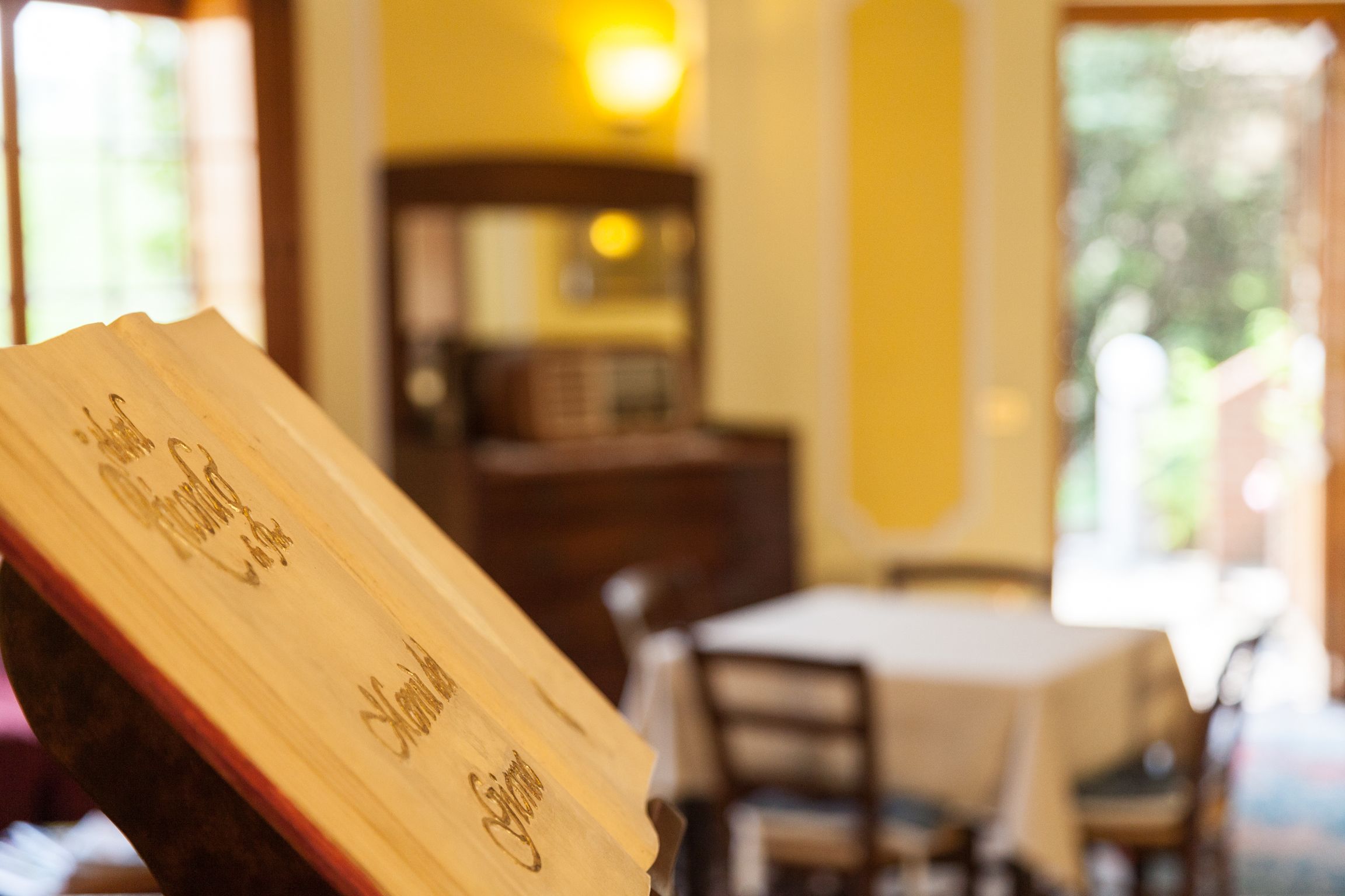 Uma mesa de madeira com texto gravado, um espelho e uma janela com vista para o verde.