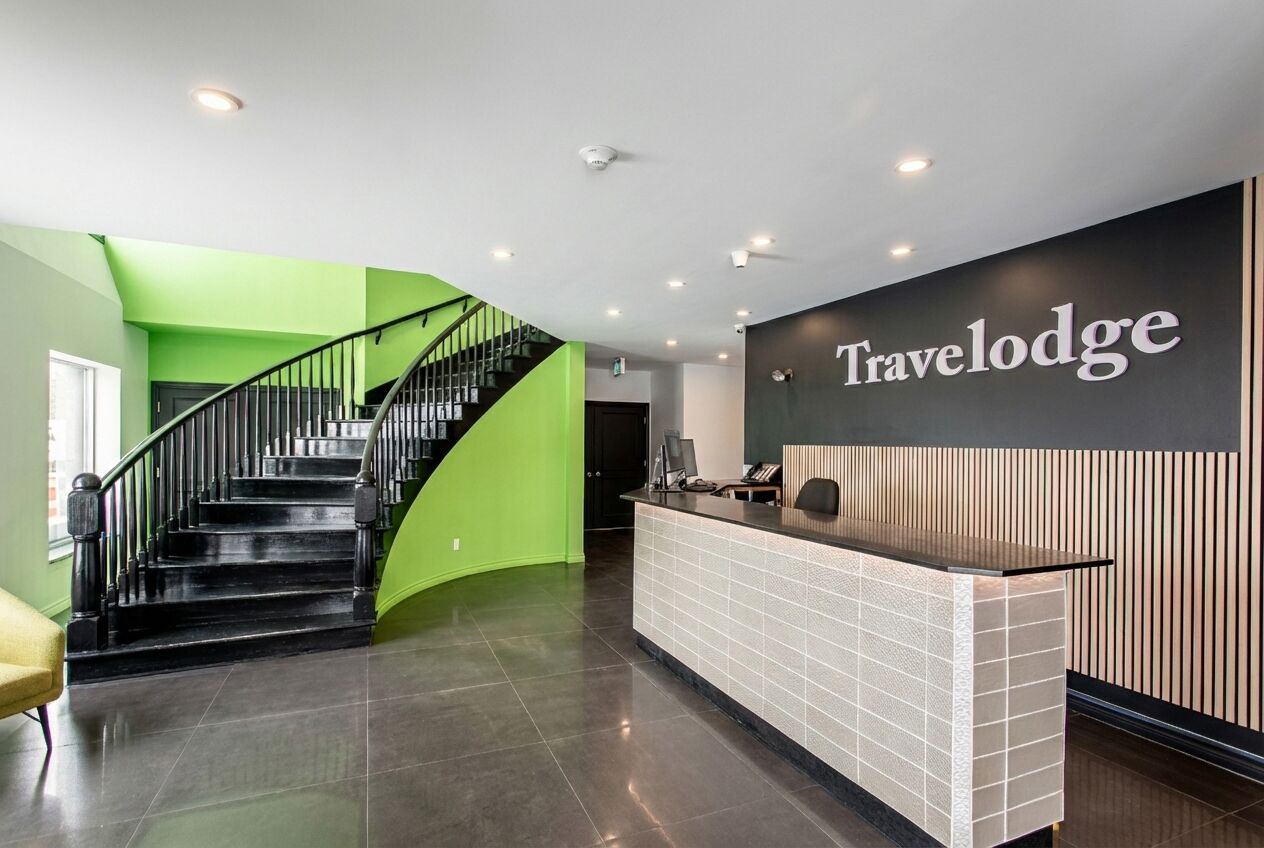 Uma área de recepção com escada, balcão e parede com a inscrição 'Travelodge'.