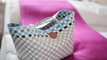Uma bolsa xadrez com fecho de metal sobre um sofá branco com almofada rosa.