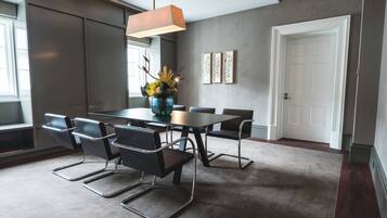Uma sala de conferências moderna, com uma mesa grande, cadeiras pretas e um vaso com flores.