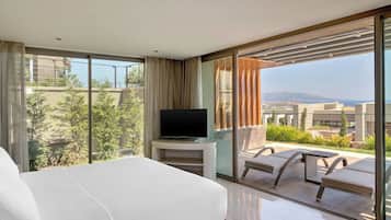 Quarto de hotel moderno com uma cama grande, televisão e varanda com área de estar.