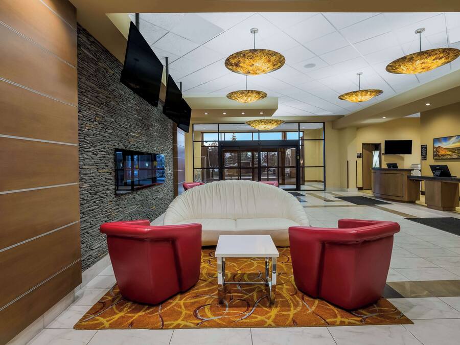 Um lobby com um sofá branco, cadeiras vermelhas, uma pequena mesa, uma parede de pedra e um balcão de recepção.