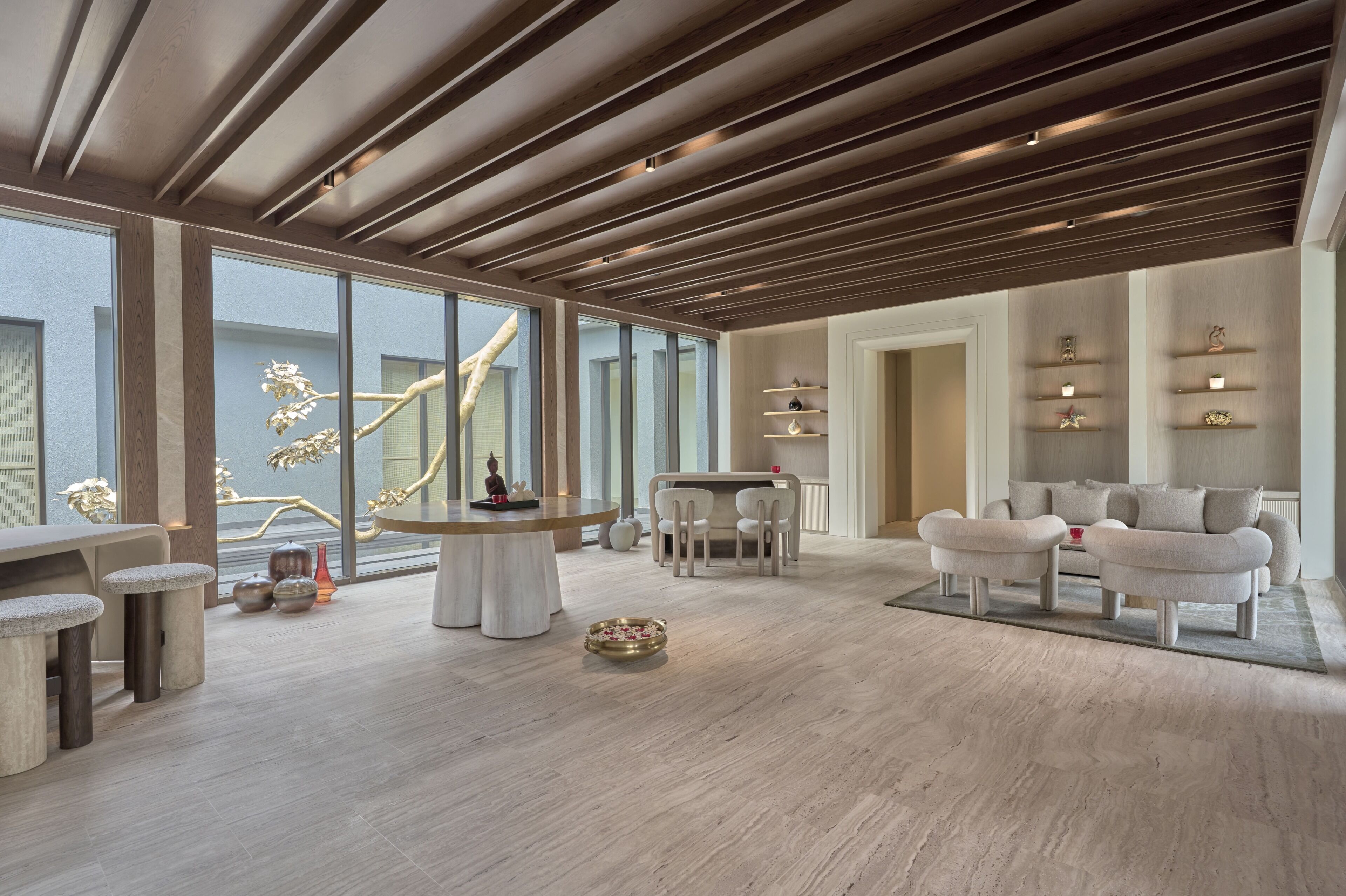 Um interior moderno com uma mesa de jantar redonda, assentos e uma escultura decorativa de árvore.