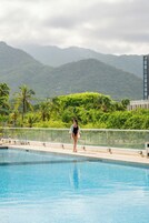 Piscina com vista para uma paisagem montanhosa e palmeiras.