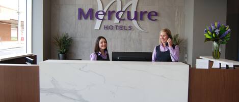 Bancada de recepção do Mercure Hotels, com tampo de mármore e design moderno.
