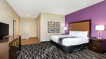 Quarto de hotel com cama, secretária, televisão e porta.