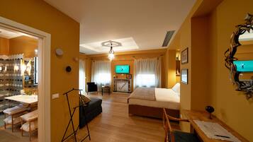Quarto de hotel com cama, escrivaninha, cadeira, televisão, lareira e banheiro visível por uma porta aberta.