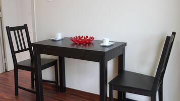 Uma mesa de jantar com duas cadeiras, uma tigela decorativa vermelha e uma caneca branca sobre a mesa.