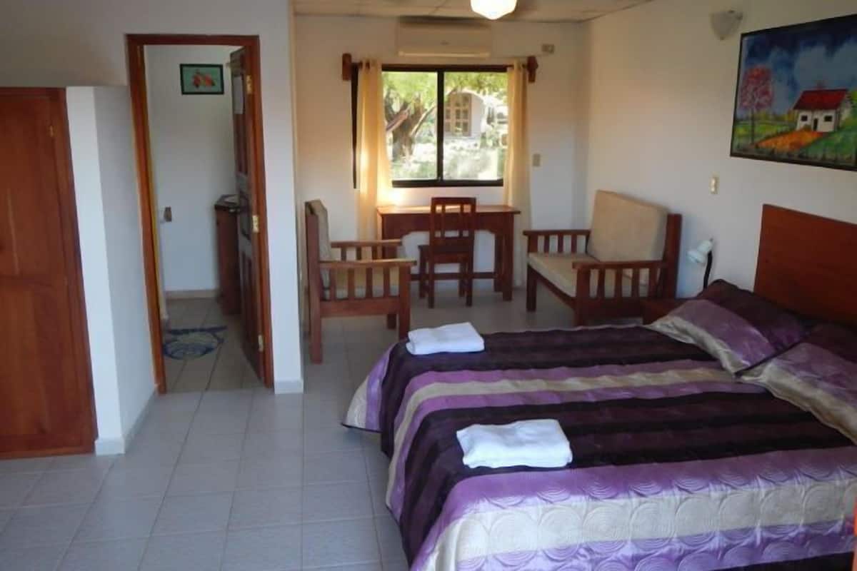 Quarto com duas camas, uma escrivaninha e uma cadeira.
