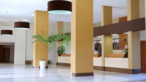 Um hall espaçoso com pé direito alto, colunas imponentes e iluminação pendente moderna.