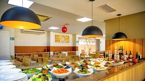 Uma área de buffet com vários pontos de comida e um bar com garrafas.
