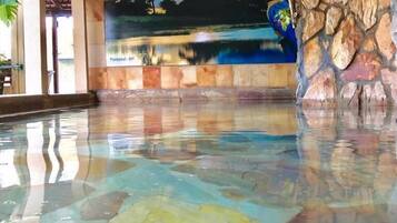 Piscina com parede de pedra e um mural de uma paisagem.
