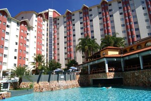 Um hotel com piscina, vários andares e fachada de pedra.