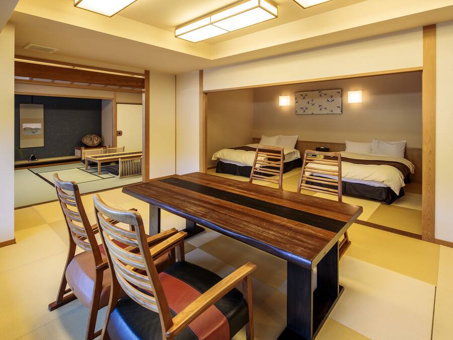 Um quarto em estilo japonês tradicional com tatames, uma mesa de madeira baixa e duas camas de solteiro.