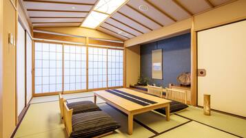 Um quarto japonês tradicional com tatames, uma mesa baixa, almofadas e uma porta de shoji.