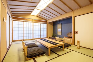Um quarto japonês tradicional com tatames, uma mesa baixa, almofadas e uma porta de shoji.