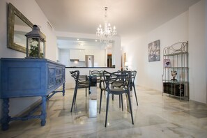 Uma sala de jantar com um candelabro, um armário azul e uma estante de metal com livros.
