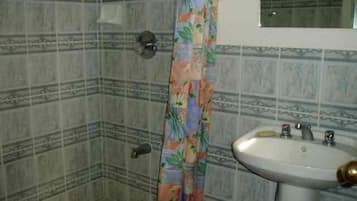 Um banheiro com azulejos estampados, cortina de chuveiro e pia.