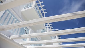Guarda-corpo de varanda branco com um céu azul transparente ao fundo.