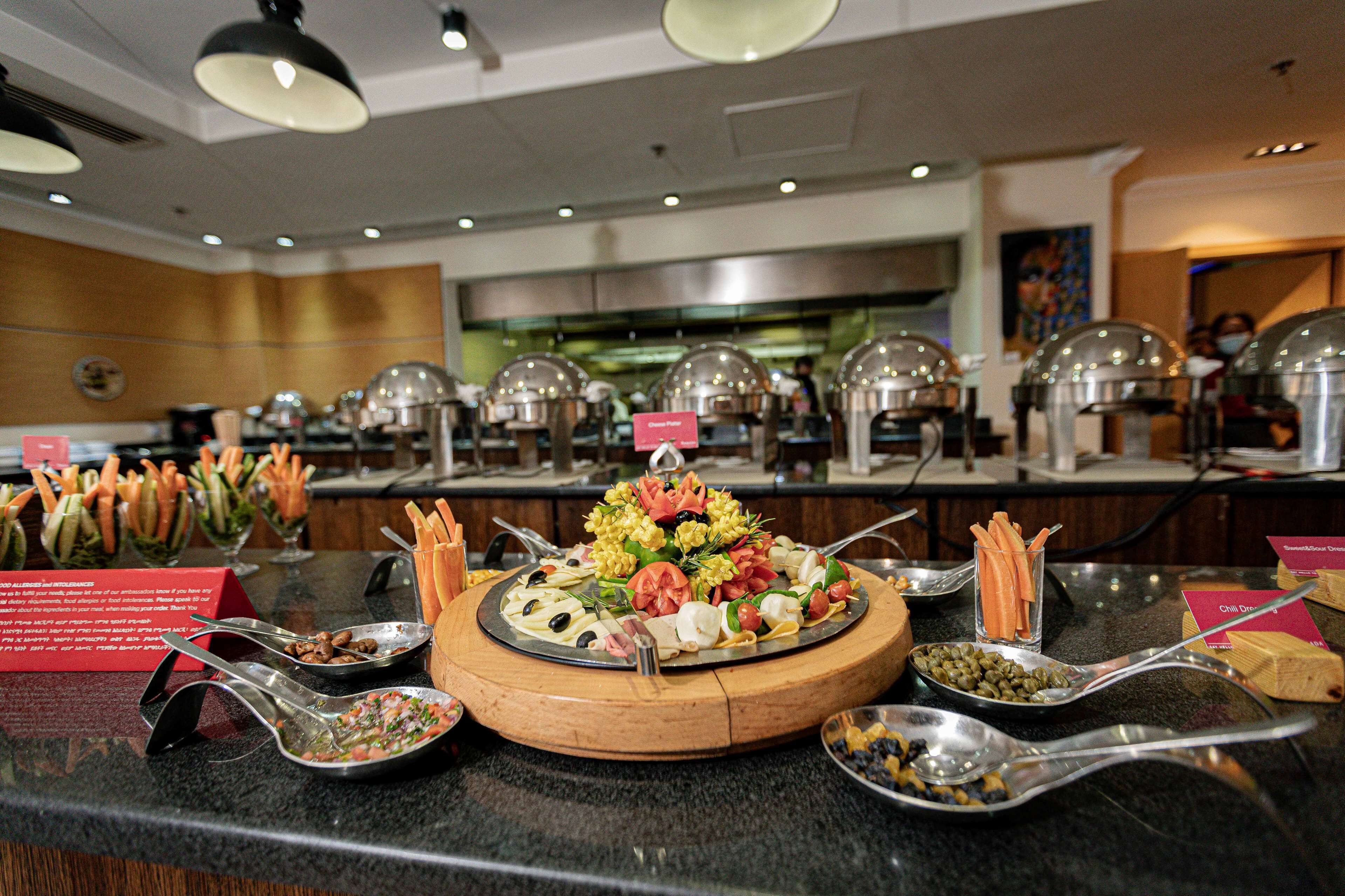 Disposição de buffet com diversos alimentos e utensílios sobre um balcão.