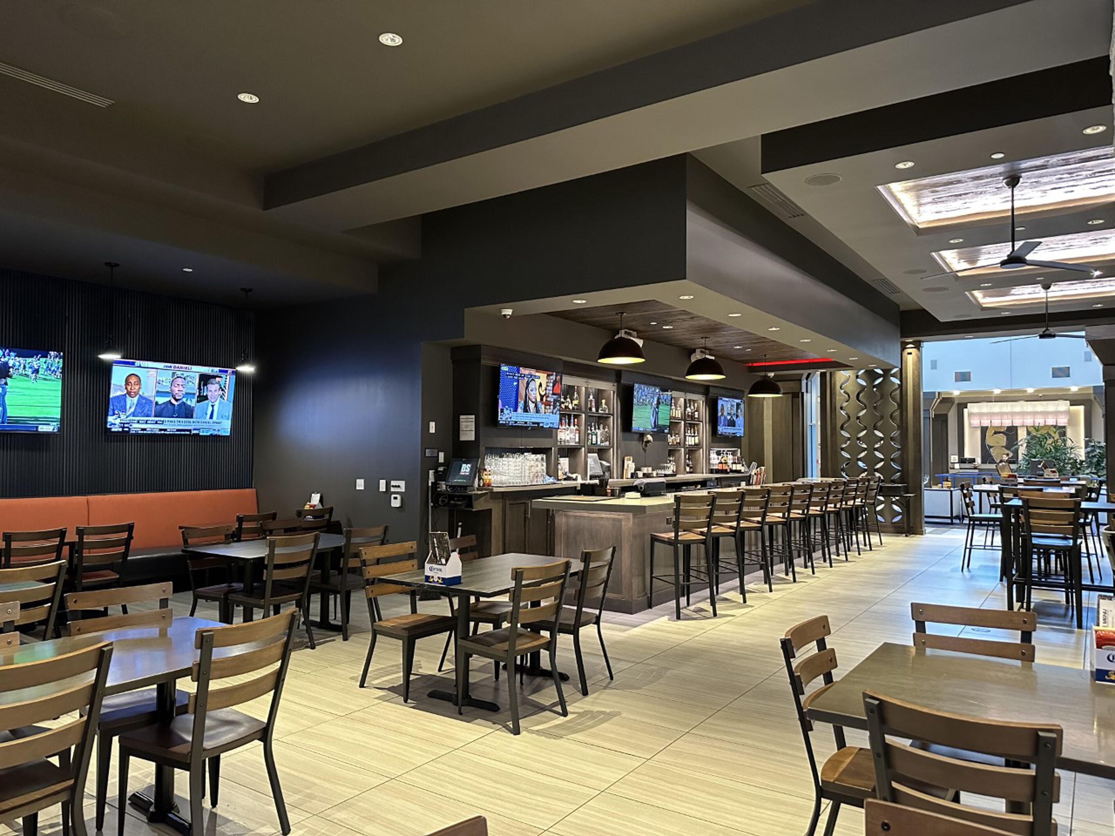 Restaurante moderno com diversas áreas de estar, incluindo um bar e cabines.