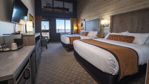 Quarto de hotel com duas camas, televisão, escrivaninha e vista do porto.