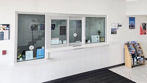Uma área de recepção com janela, um mural de avisos e um balcão de check-out.