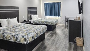 Quarto de hotel com duas camas, uma escrivaninha, uma cadeira e uma televisão.