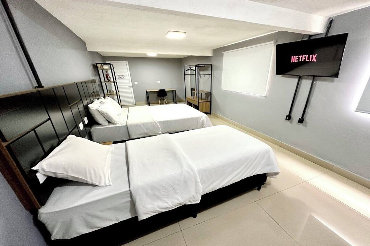 Quarto de hotel com duas camas, televisão e guarda-roupa.