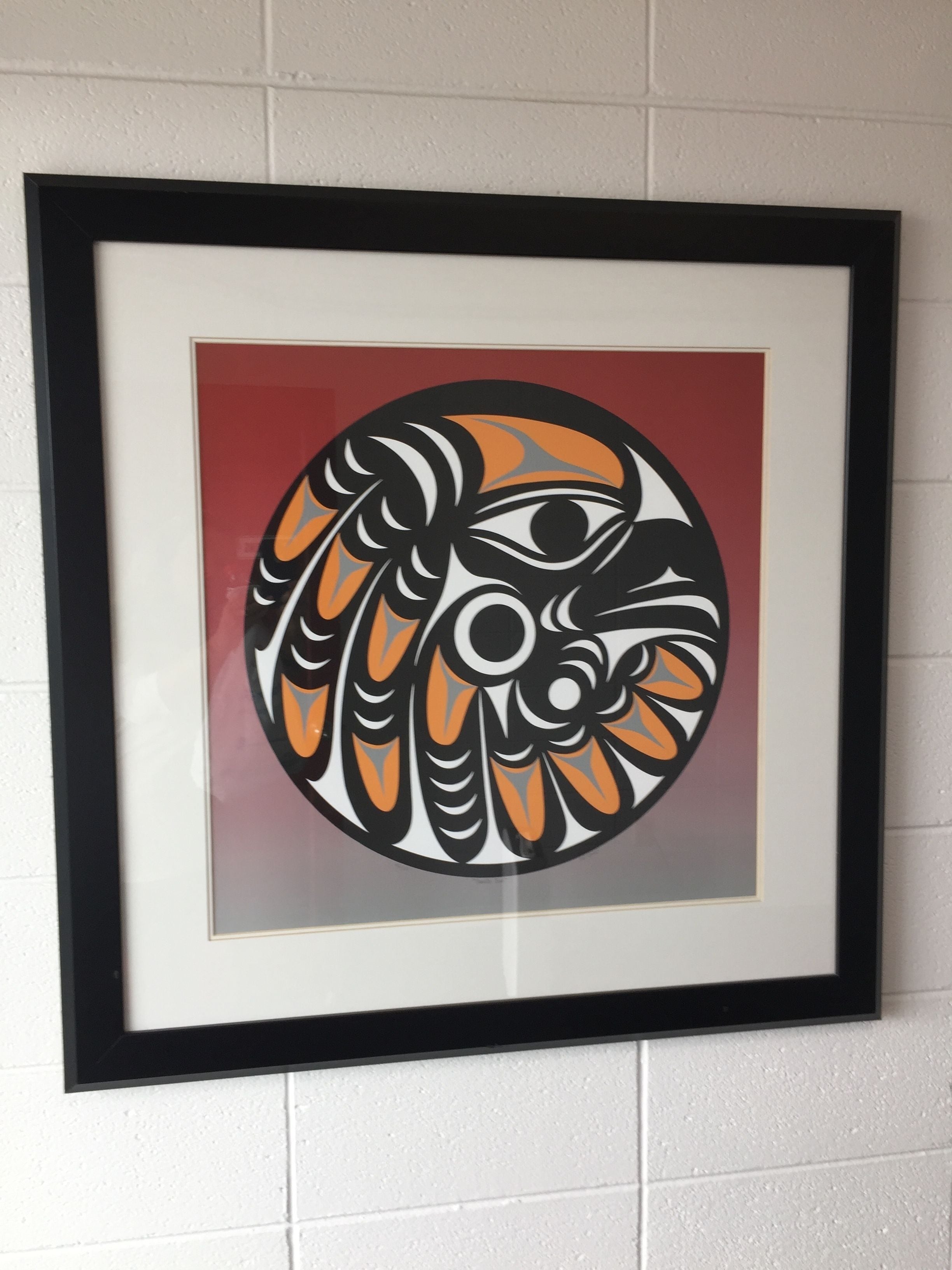 Uma obra de arte emoldurada com um design circular numa parede branca.