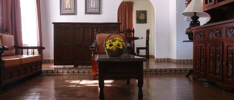 Um quarto com piso de madeira, um sofá, uma mesa com um vaso de flores e um armário.