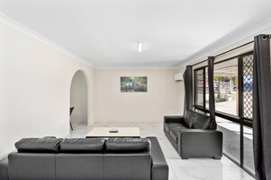 Uma sala de estar moderna com sofá, mesa de centro e uma janela grande com cortinas.