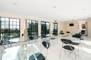 Uma sala de conferências com mesas e cadeiras de vidro, amplas janelas e um sinal de saída.