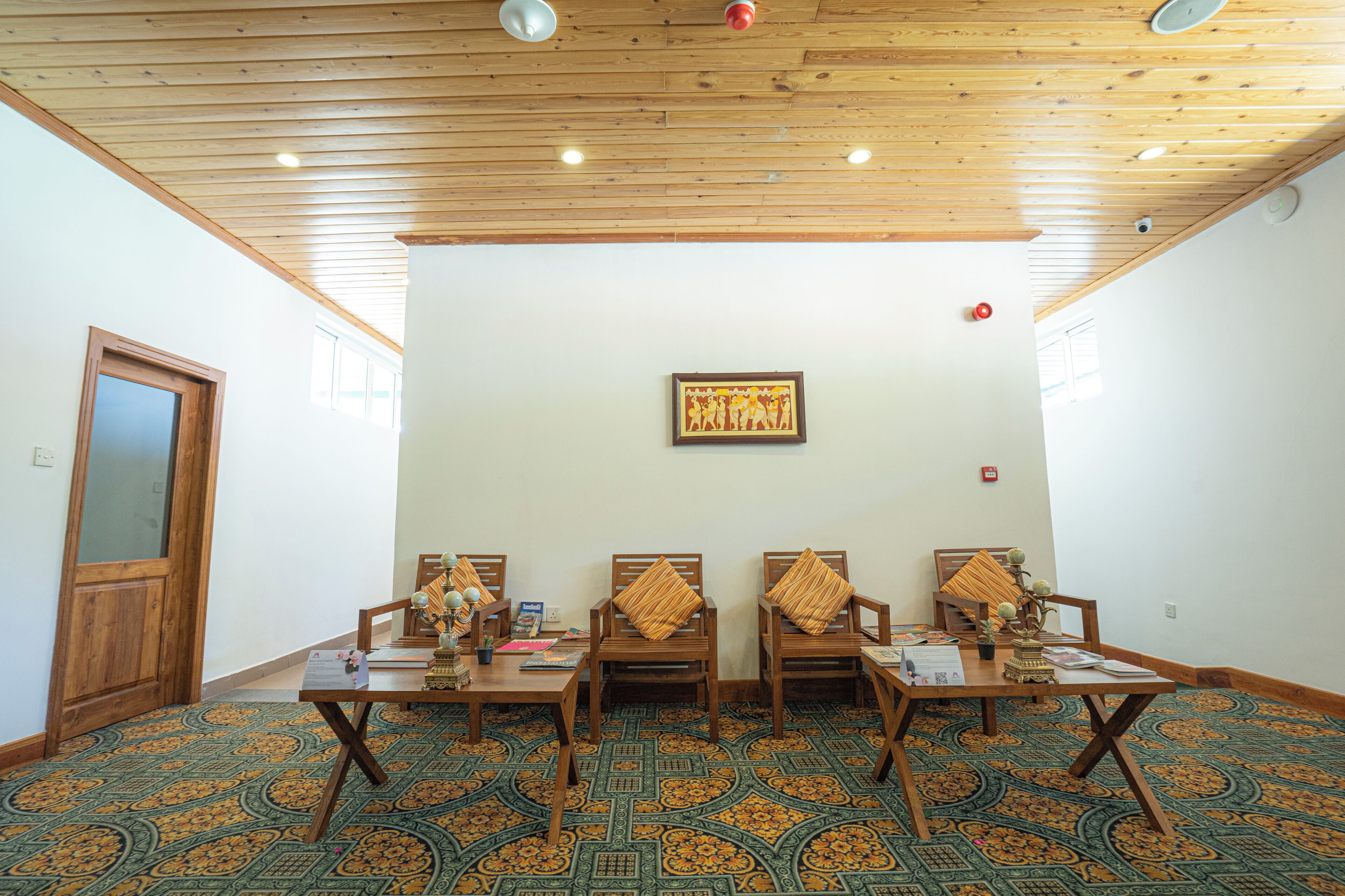 Uma sala de conferências com teto de madeira, carpete estampado e um quadro na parede.