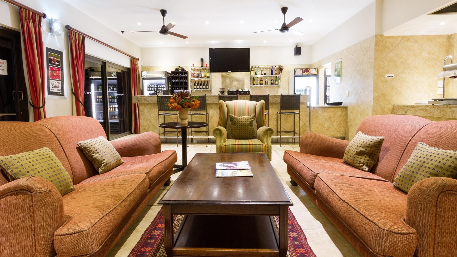 Uma sala de estar com dois sofás, uma mesa de centro, uma televisão e uma área de cozinha ao fundo.