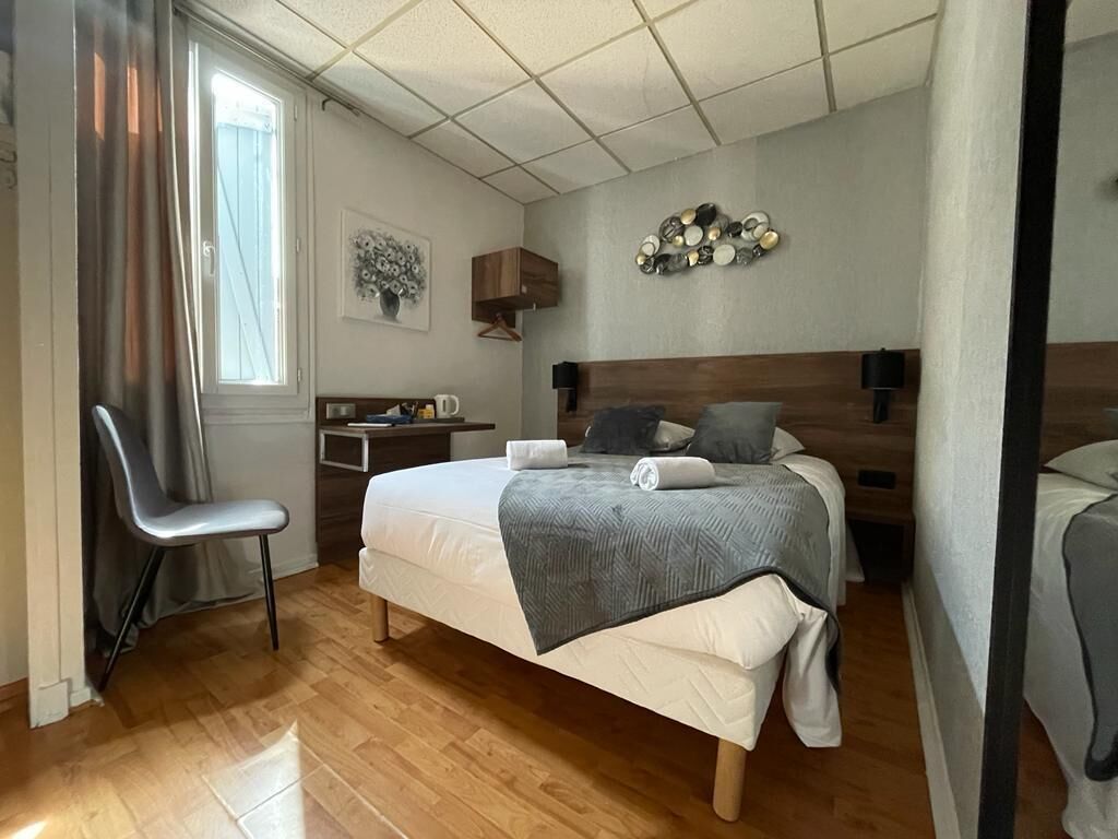 Quarto com cama, cadeira, mesa de cabeceira e um objeto decorativo na parede.