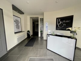 Uma área de recepção com balcão, um aviso com a inscrição "Bethune City Relax" e um quadro de informações fixado na parede.