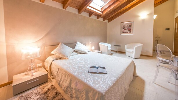 Quarto com cama, mesa de cabeceira, abajur e uma cadeira.