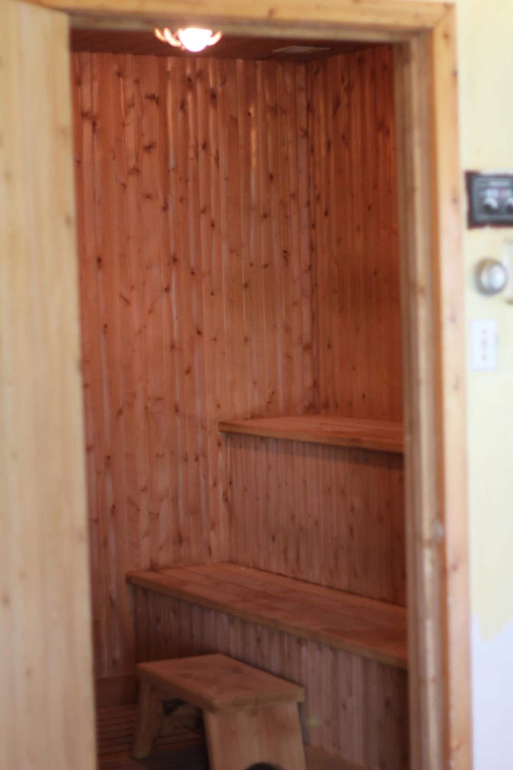 Uma sala de sauna de madeira com bancos e uma pequena mesa.