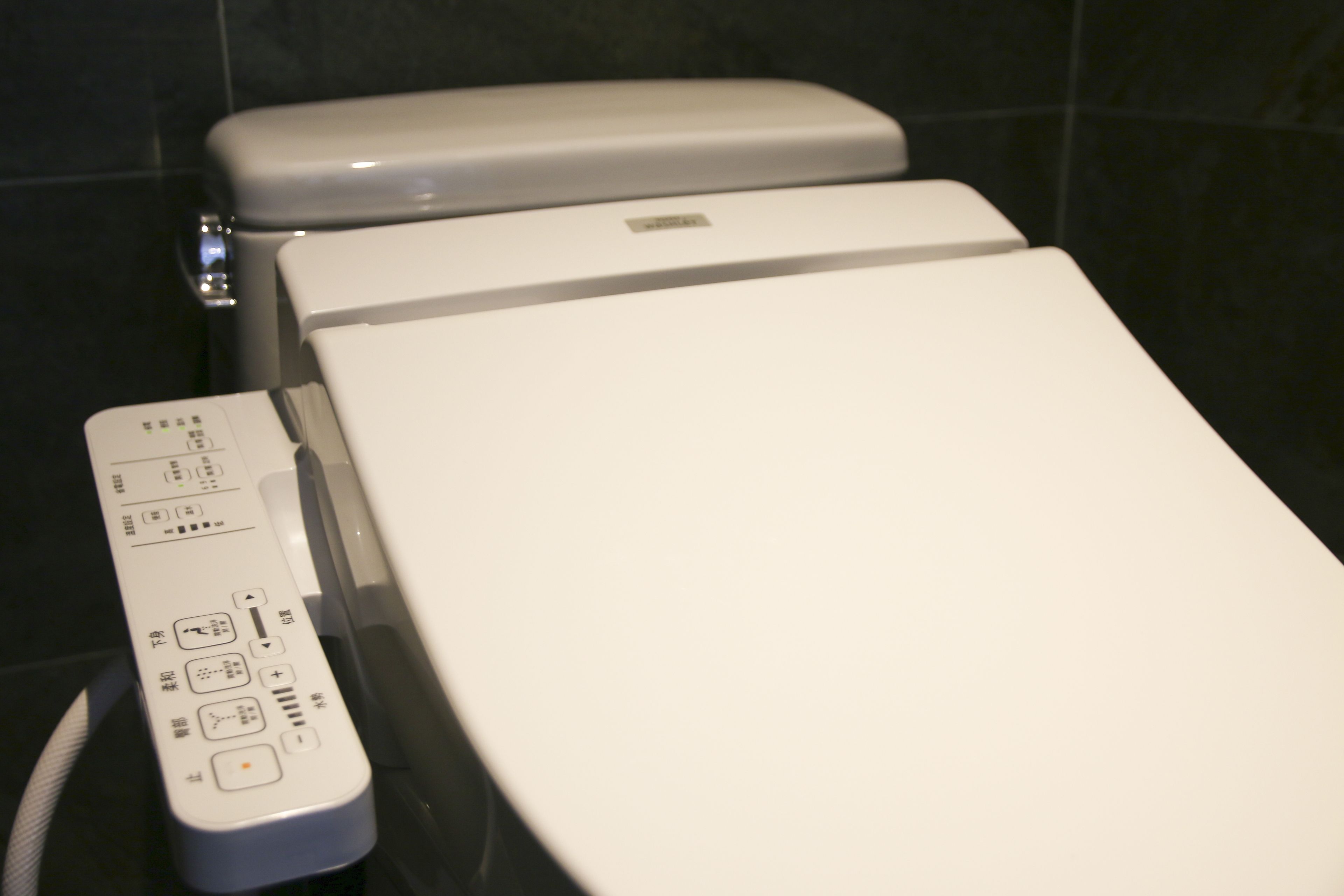 Sanitário branco com painel de controle, incluindo botões e visor.